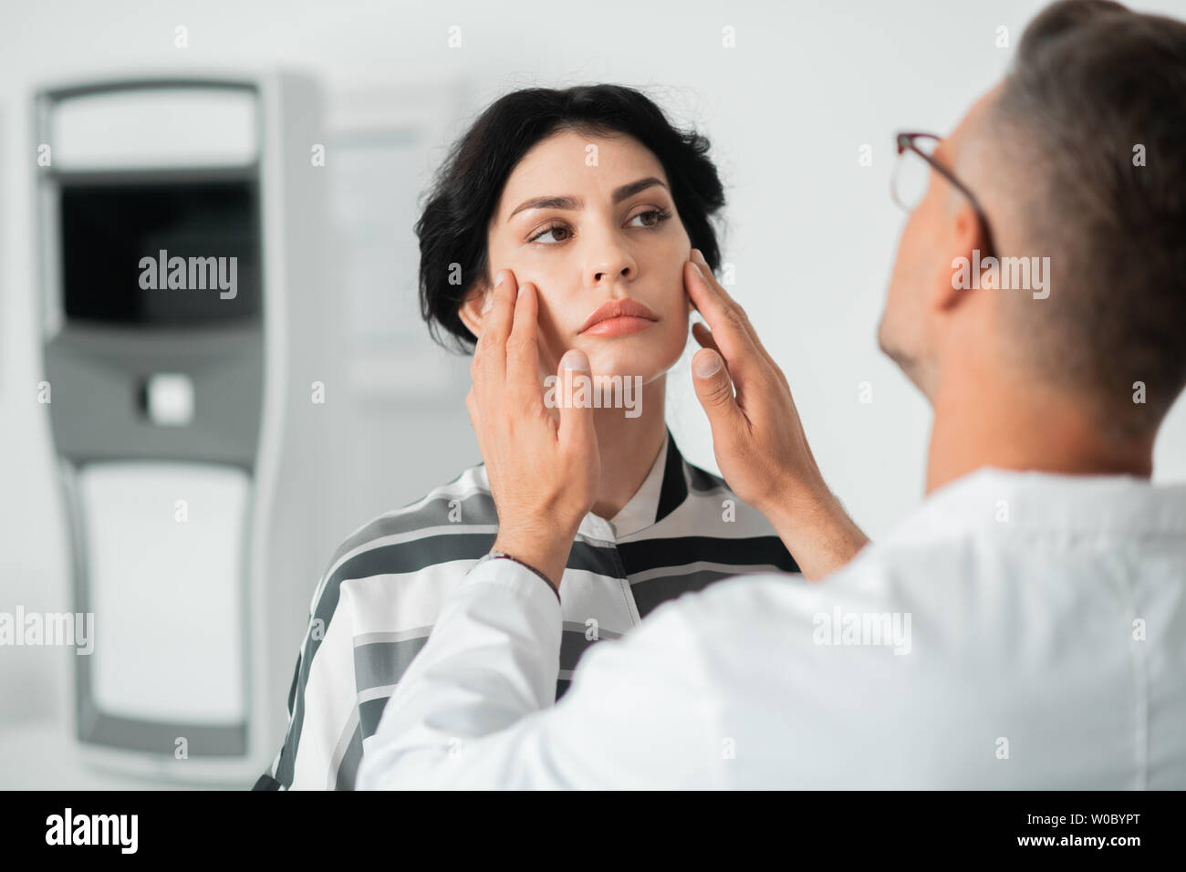 Plastic surgeon putting hands on face while examining before surgery ...