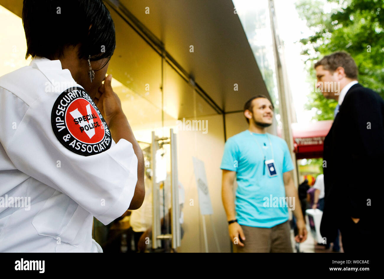 A security guard looks on as people wait in line outside of the Apple ...
