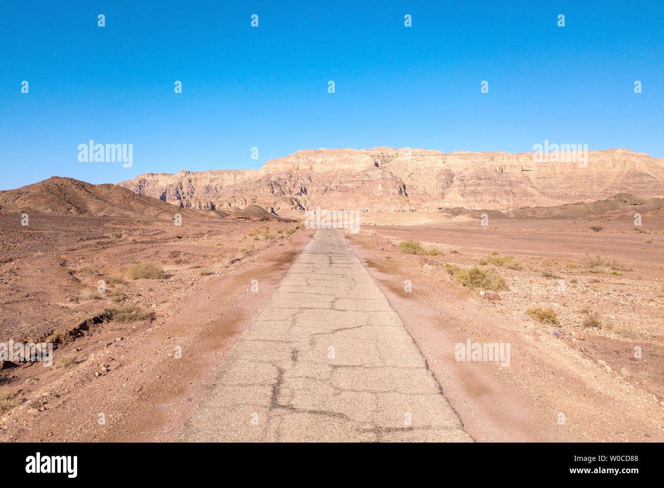 Long stretch of an old Desert road with mountains and blue sky in the ...