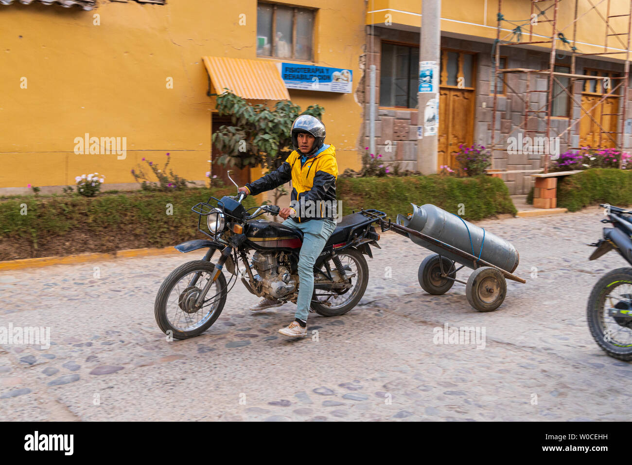 Man on motorcycle towing cart with propane gas bottle, Ollantaytambo ...