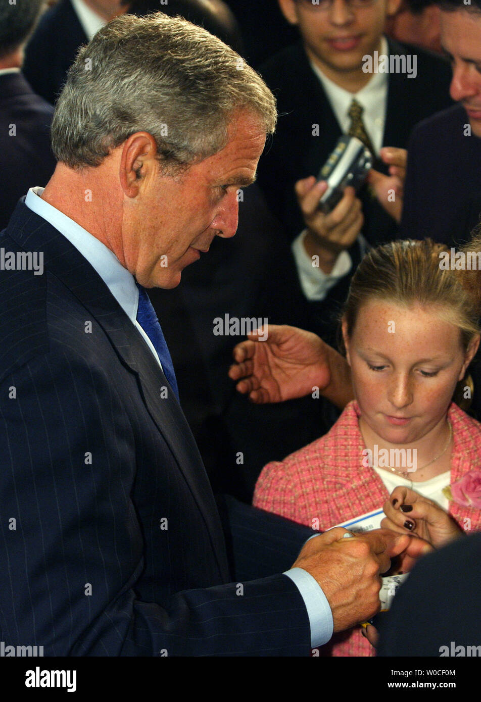 President George W. Bush signs autographs while Meghan Overend looks on ...