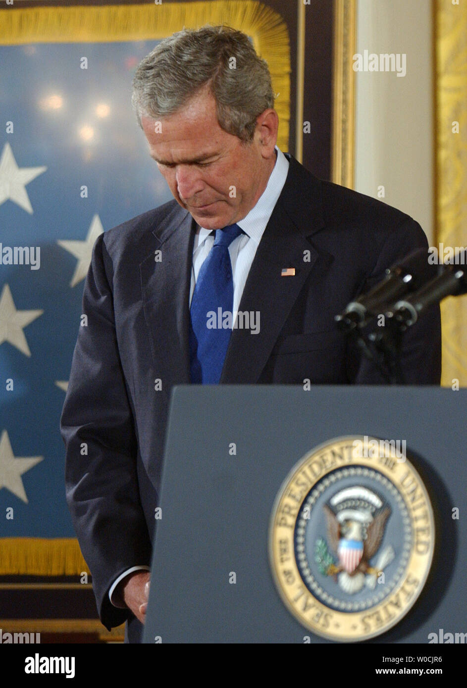 U.S. President George W. Bush bows his head in prayer before speaking ...