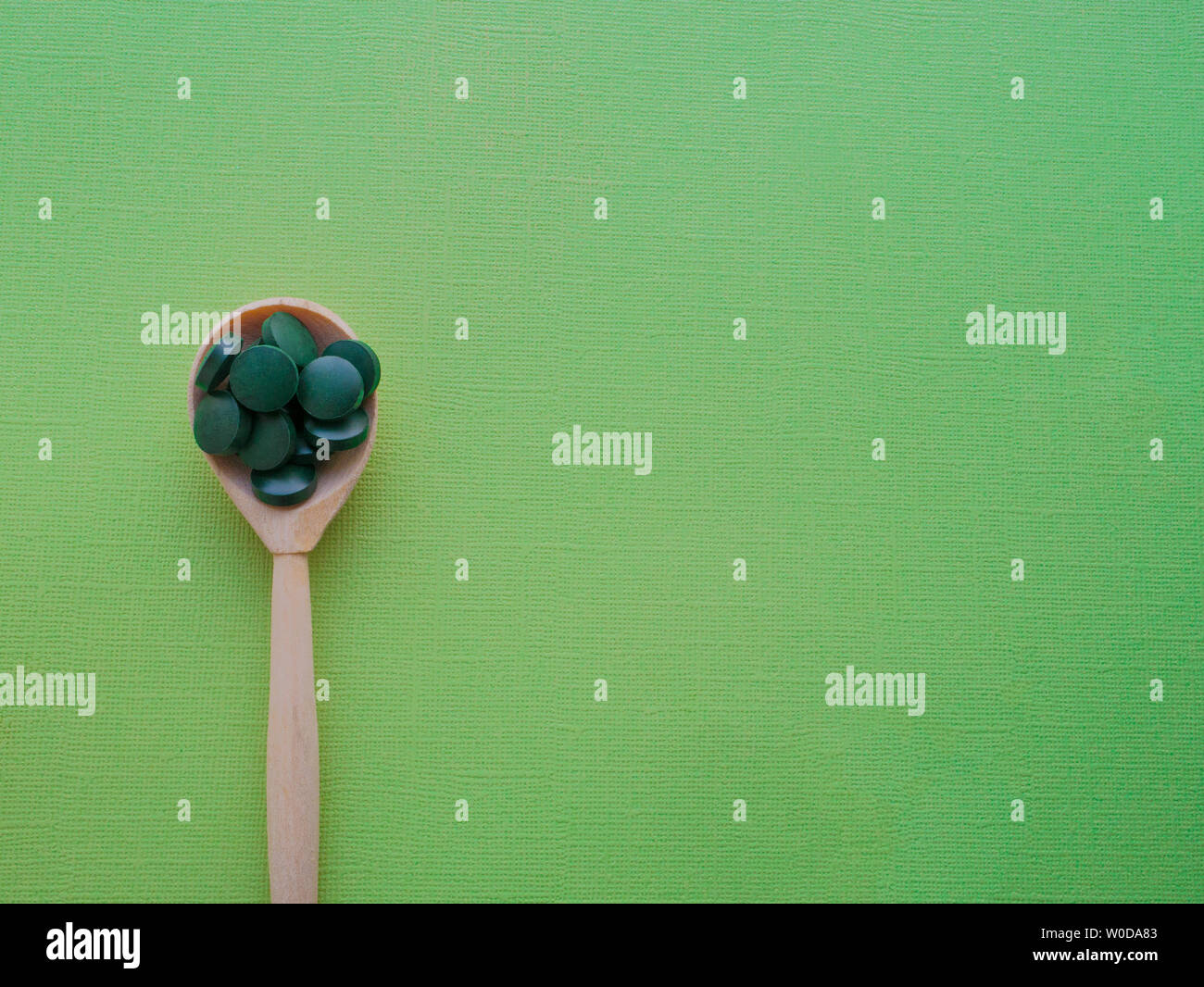 Spirulina algae tablets on green background from top view Stock Photo ...