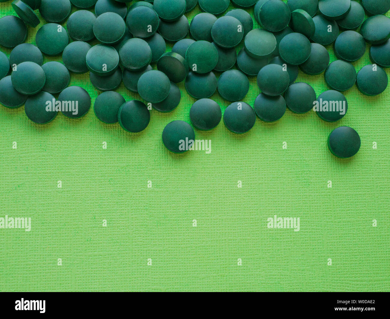 Spirulina algae tablets on green background from top view Stock Photo ...