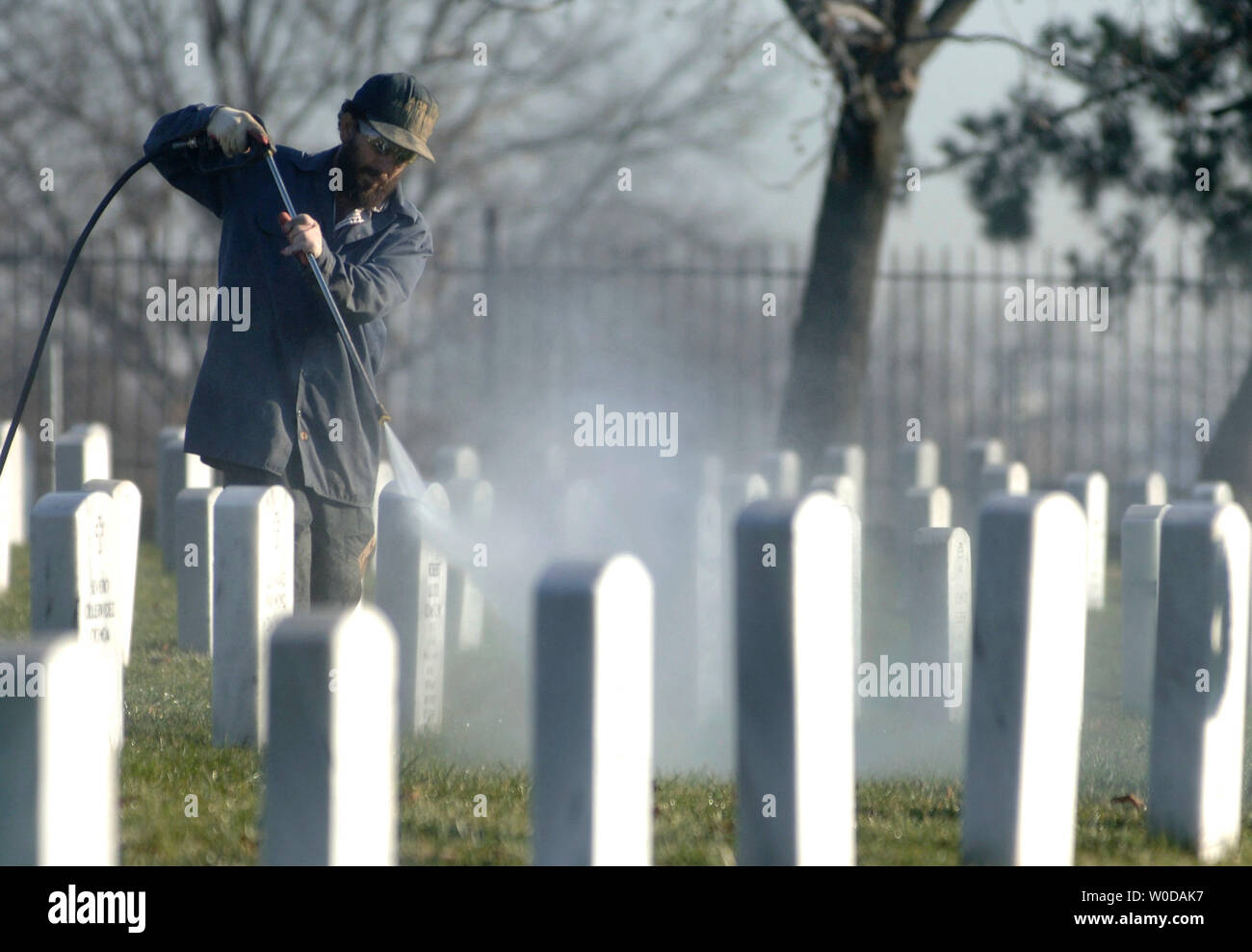 A maintenance worker cleans headstones at Arlington National Cemetery ...