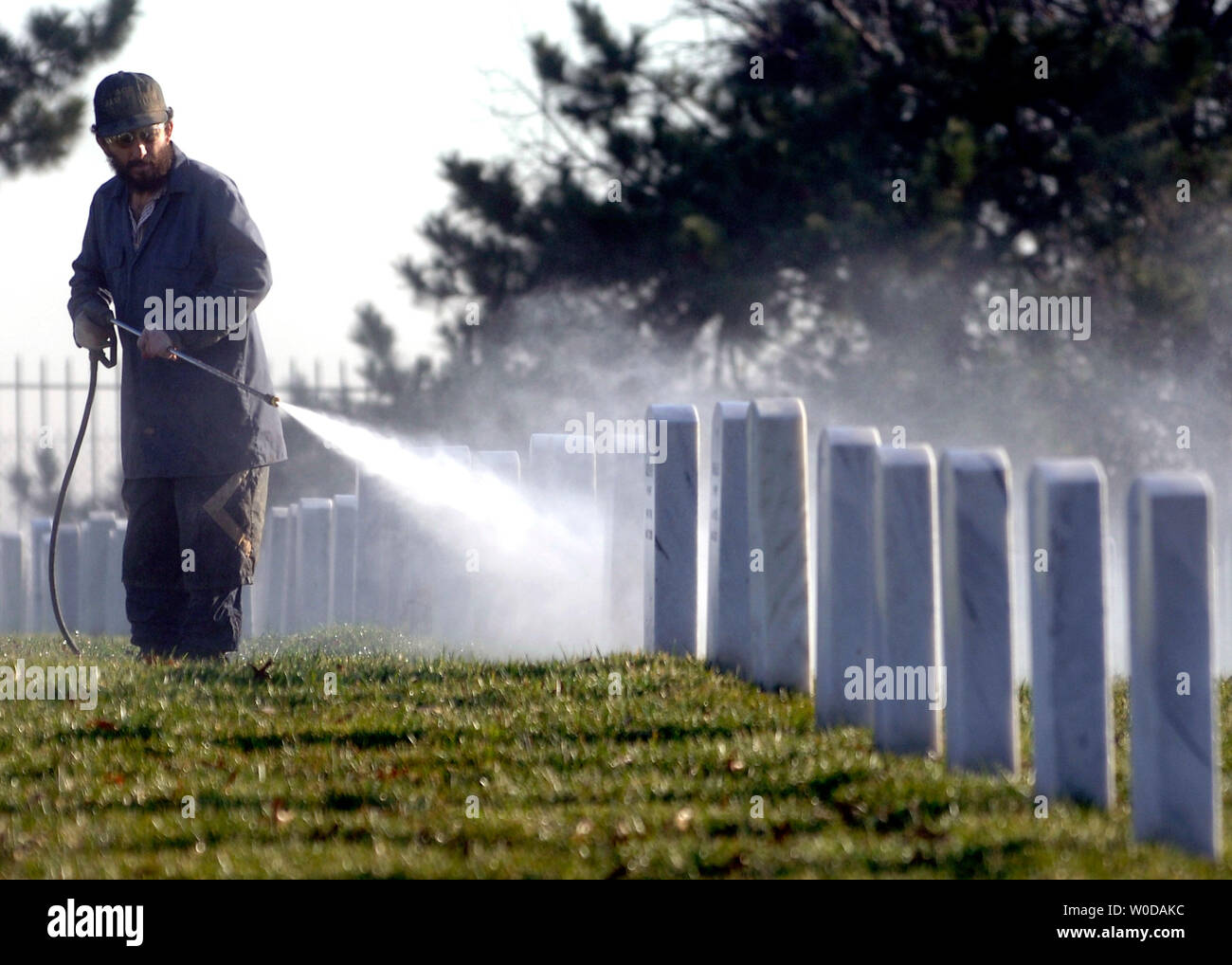 A maintenance worker cleans headstones at Arlington National Cemetery ...