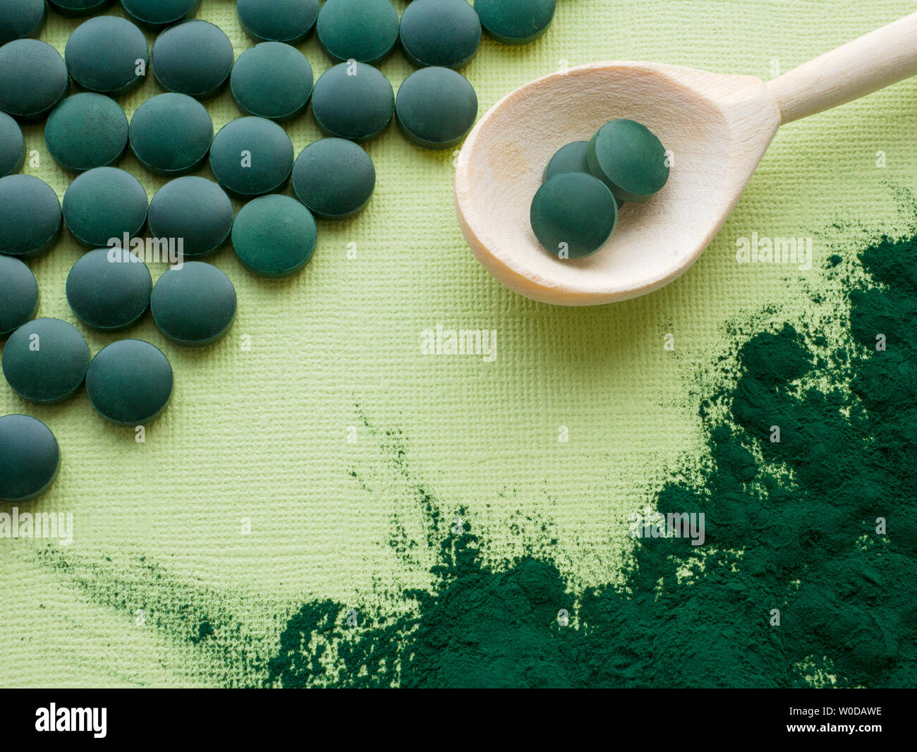 Spirulina algae tablets and powder on green background from top view ...