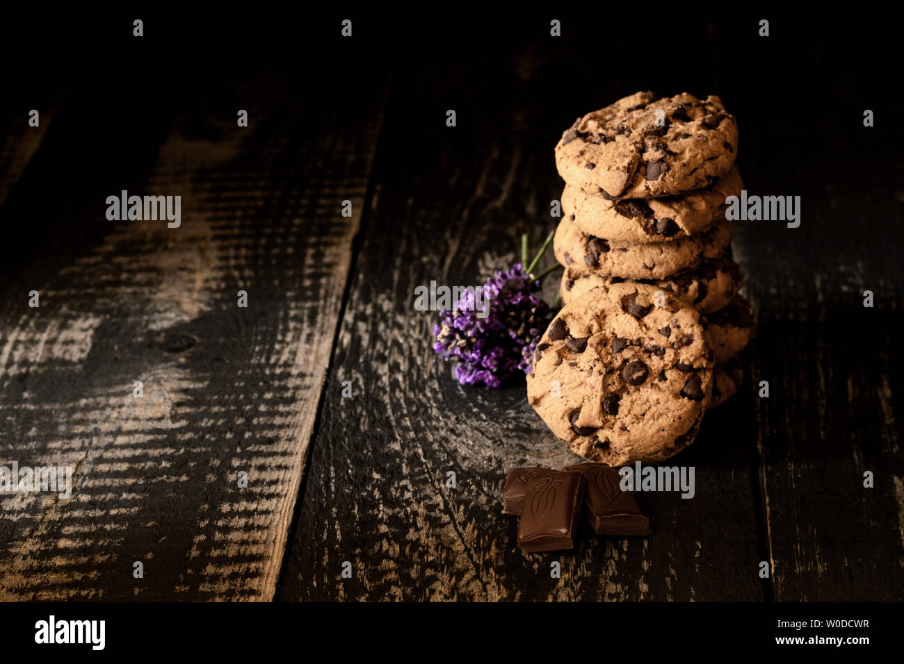 Column of cookies with chocolate bars in background of old black planks ...