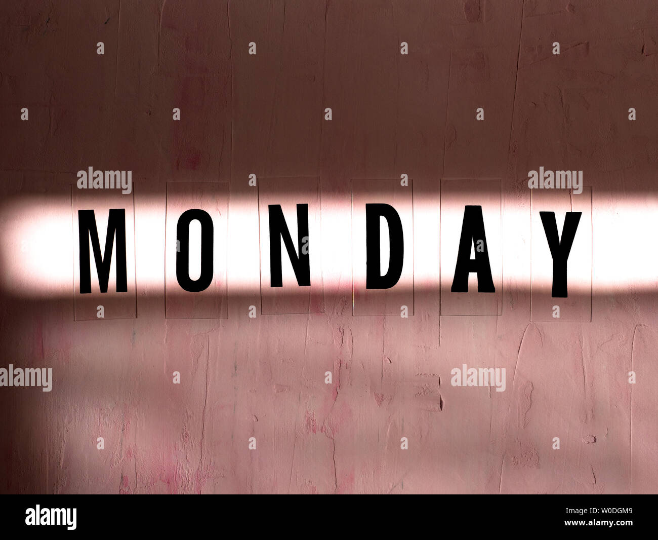 Word MONDAY with shadow of light on light pink background. Top view ...