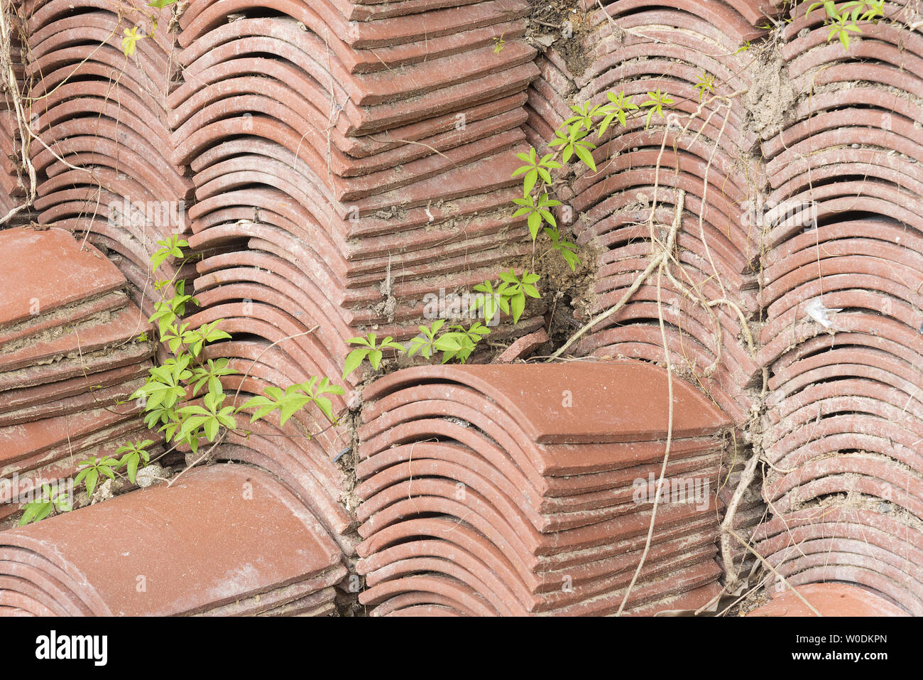 Terracotta roof tiles stacked ready for use with a symmetrical pattern ...