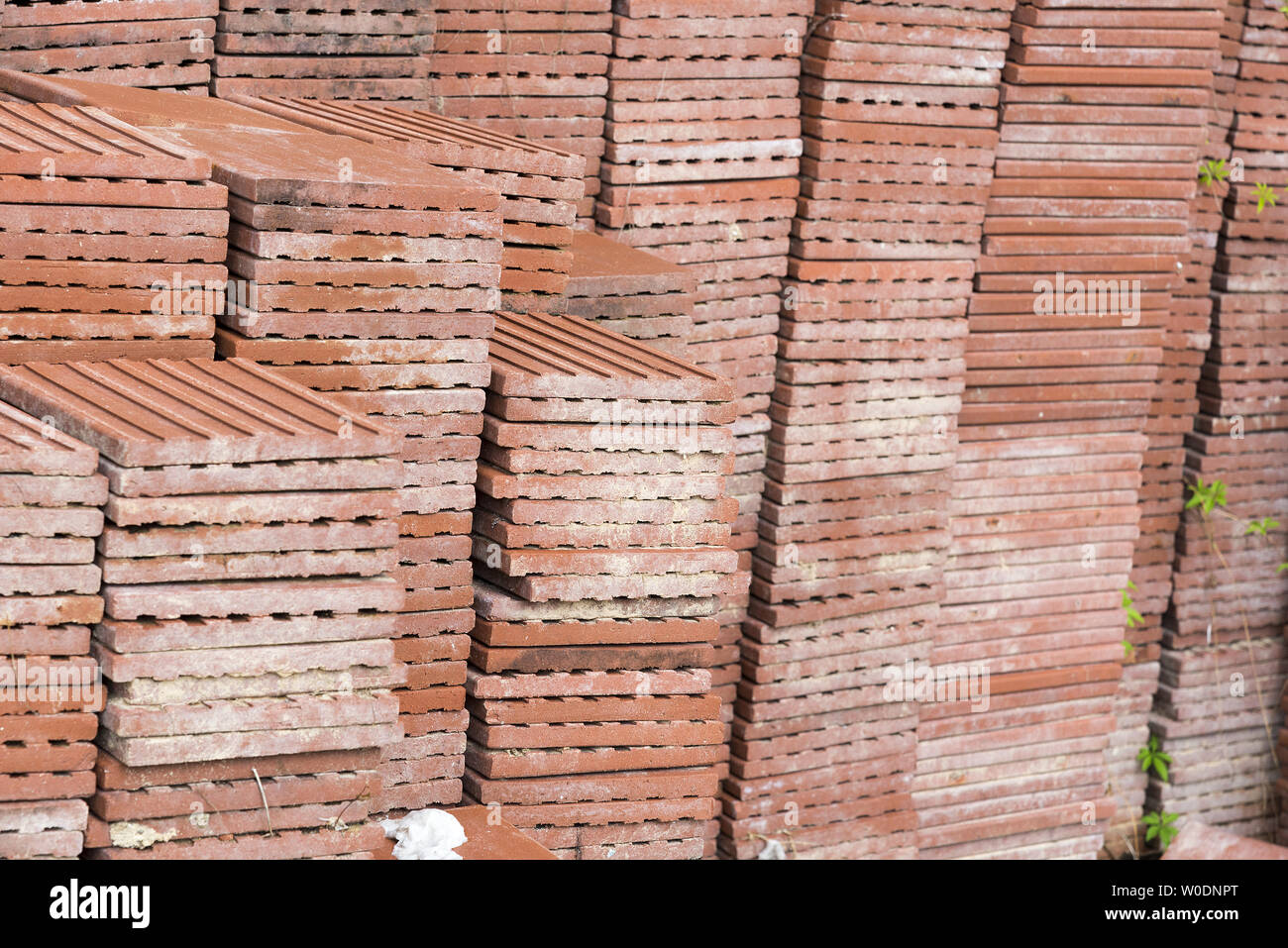 Terracotta roof tiles stacked ready for use with a symmetrical pattern ...