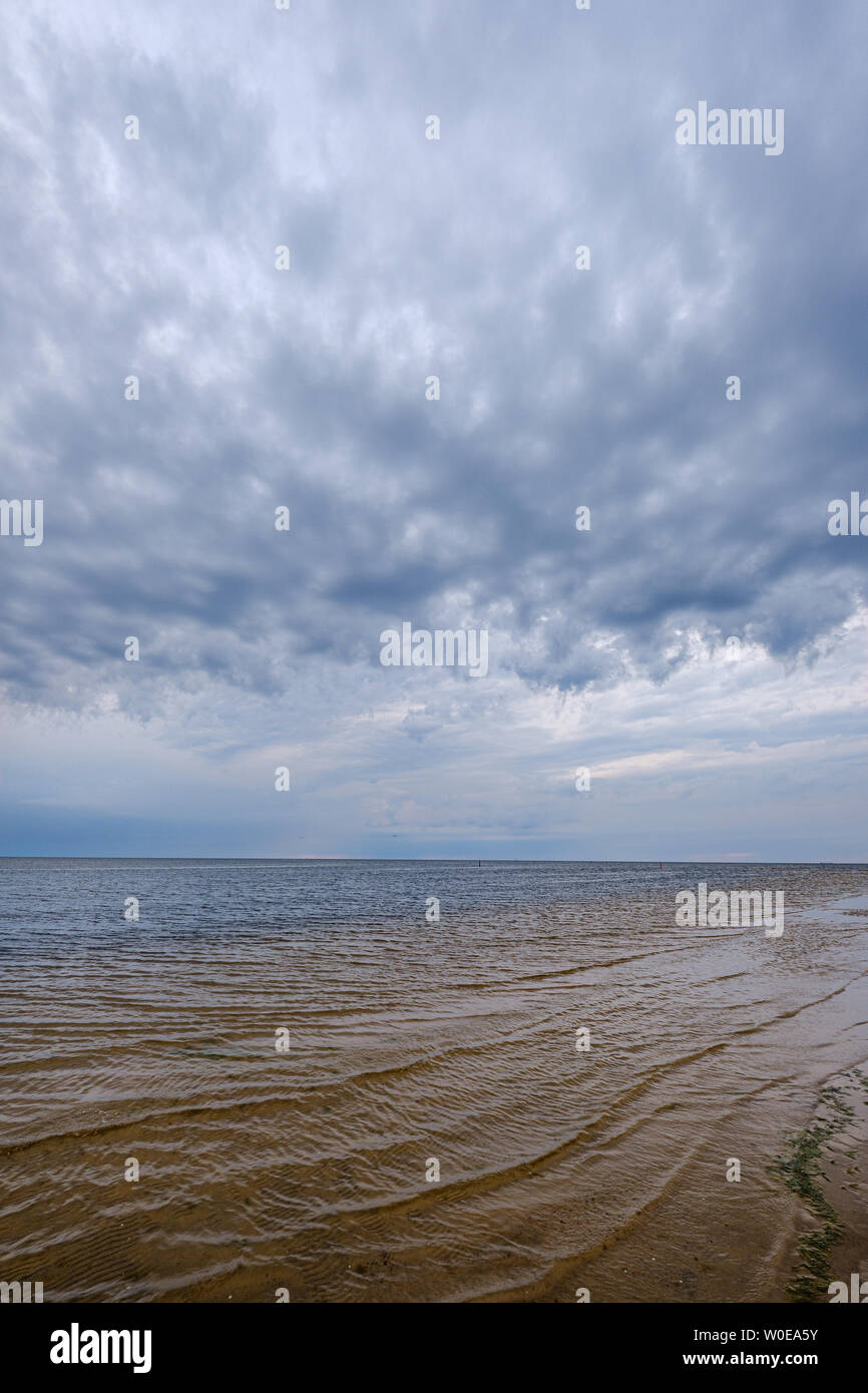 dramatic colorful clouds over sandy beach at the sea with blue sky and ...