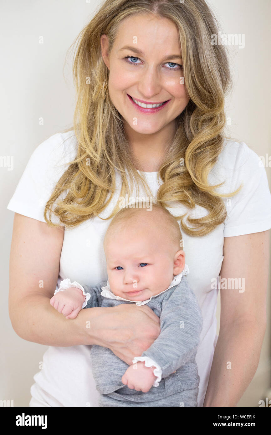 Beautiful smiling young mother carrying her 2 month old baby on her ... Beautiful smiling young mother carrying her 2 month old baby on her ...