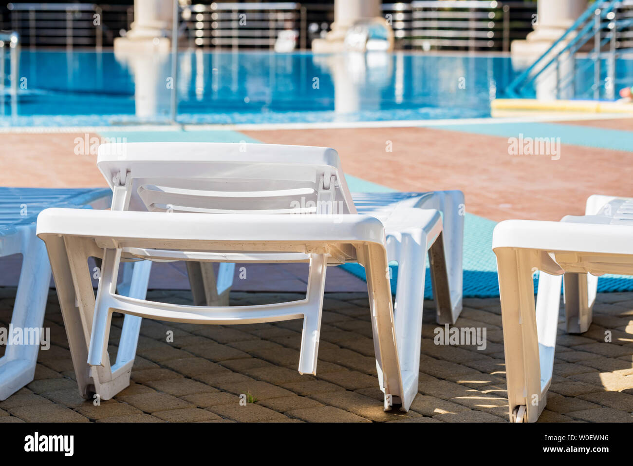 Empty plastic white deck chairs near the swimming pool Stock Photo - Alamy