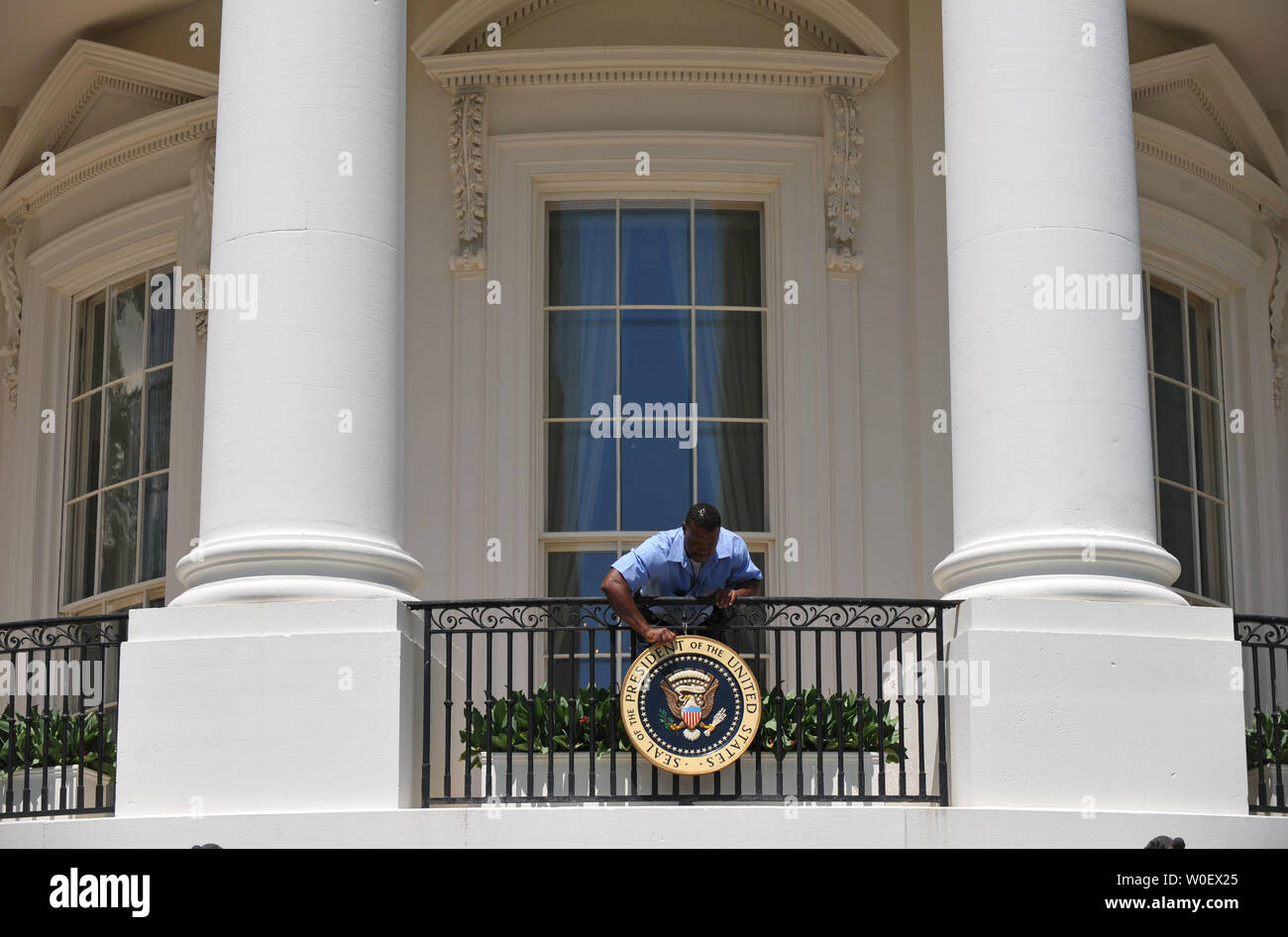 A White House employee straitens the presidential seal before an event ...