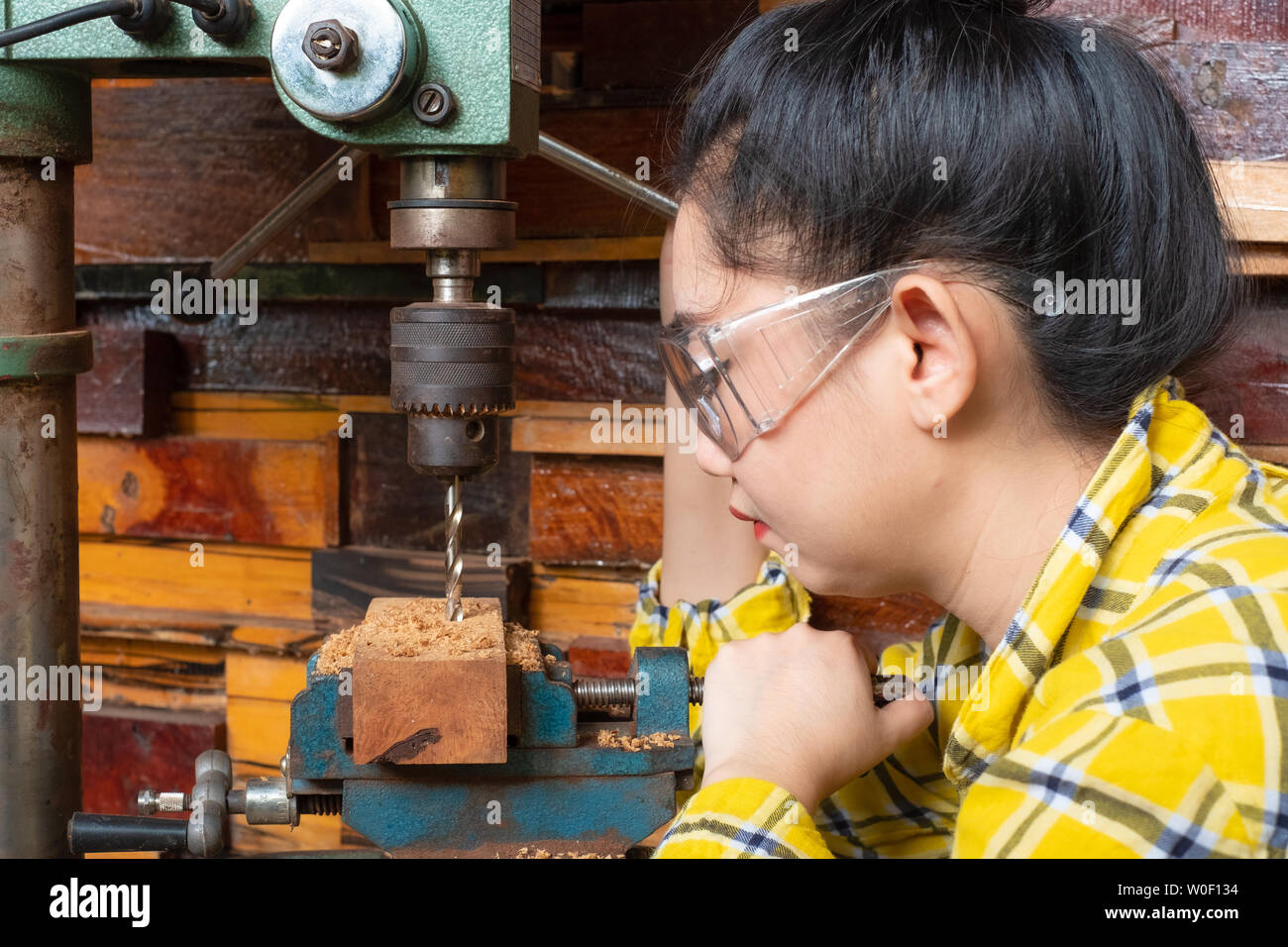 Women standing is craft working drill wood at a work bench with Drill ...