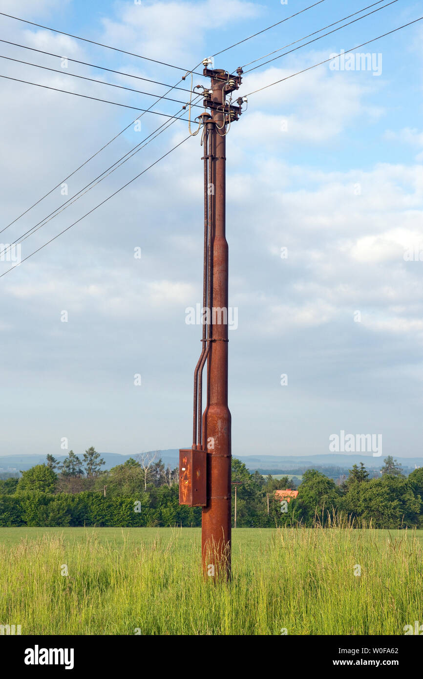 Old electric pole with three sets of wiring in the field with sky and ...