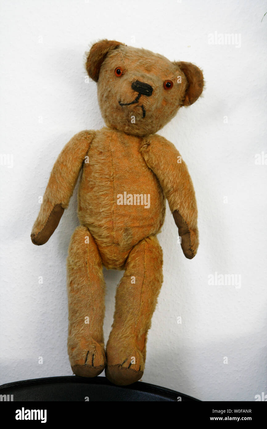 Old stuffed and sewn Teddybear doll standing on a pillow leaning ...