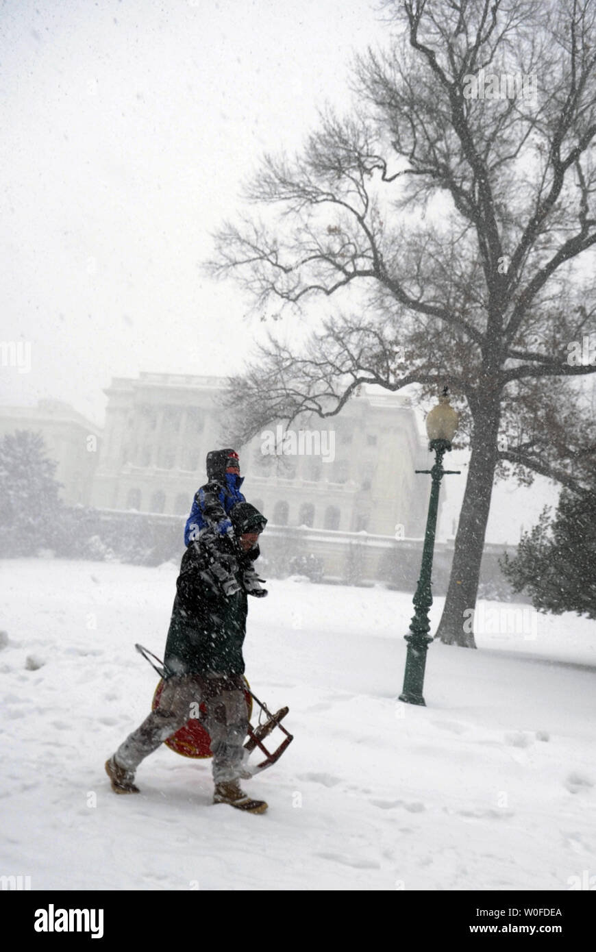A father and child walk with a sled in hand near the U.S. Capitol in ...
