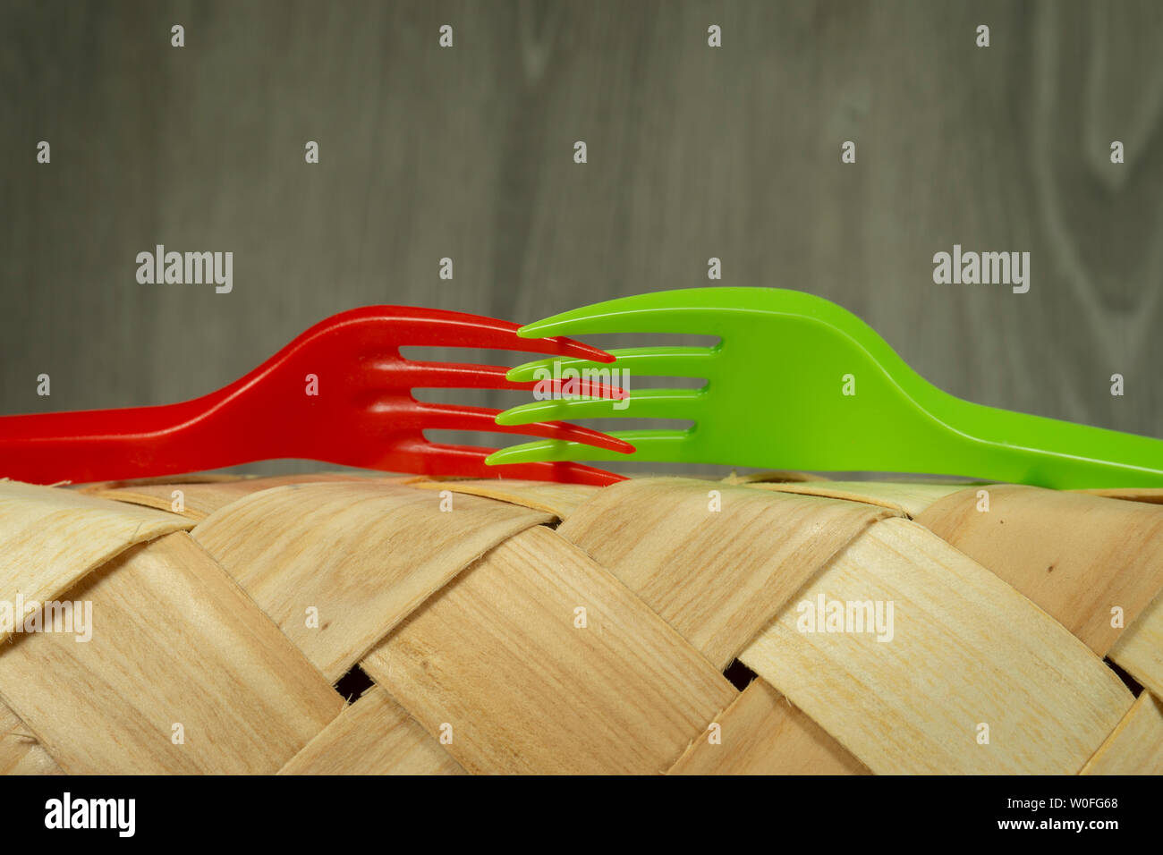 Colorful plastic forks and tipped wicker basket in close-up. Plastics ...