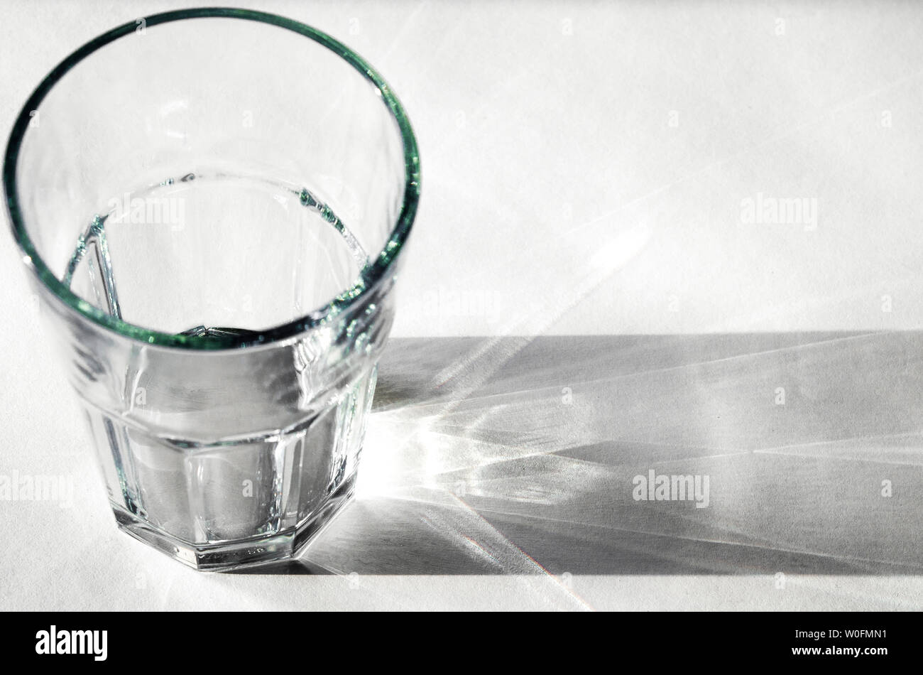 Water glass with strong shadows on white background Stock Photo - Alamy