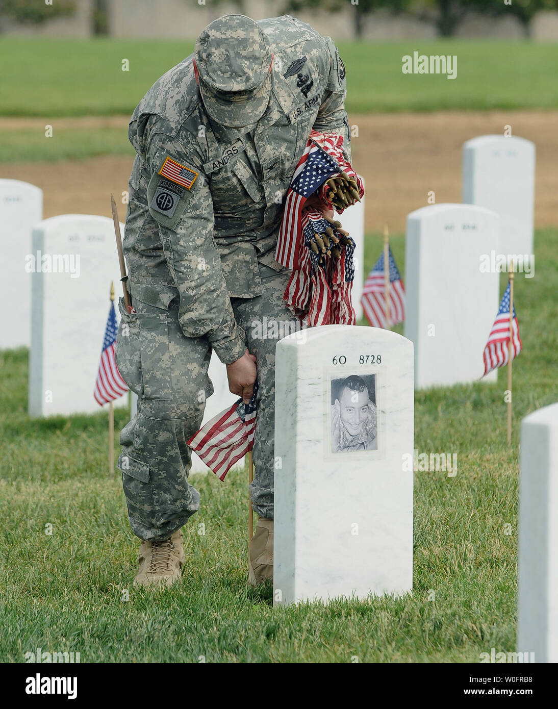 A soldier places an American Flag in front of the grave of U.S. Army PFC George Howell, who died ...