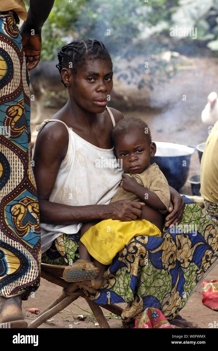 An Aka Pygmy woman holds a young child in their remote African jungle ...