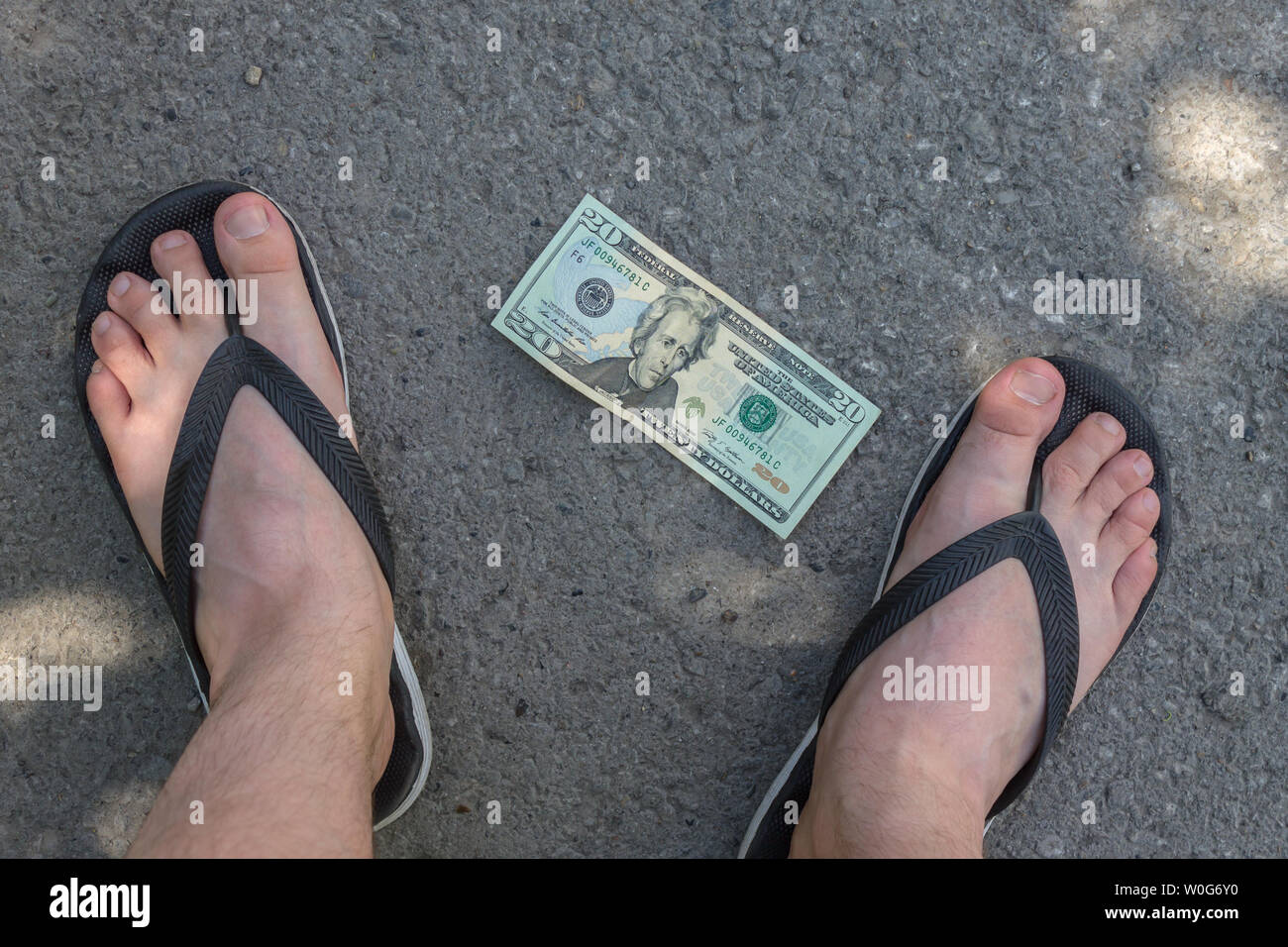 The money lies on the pavement under the feet of a young man in flip ...
