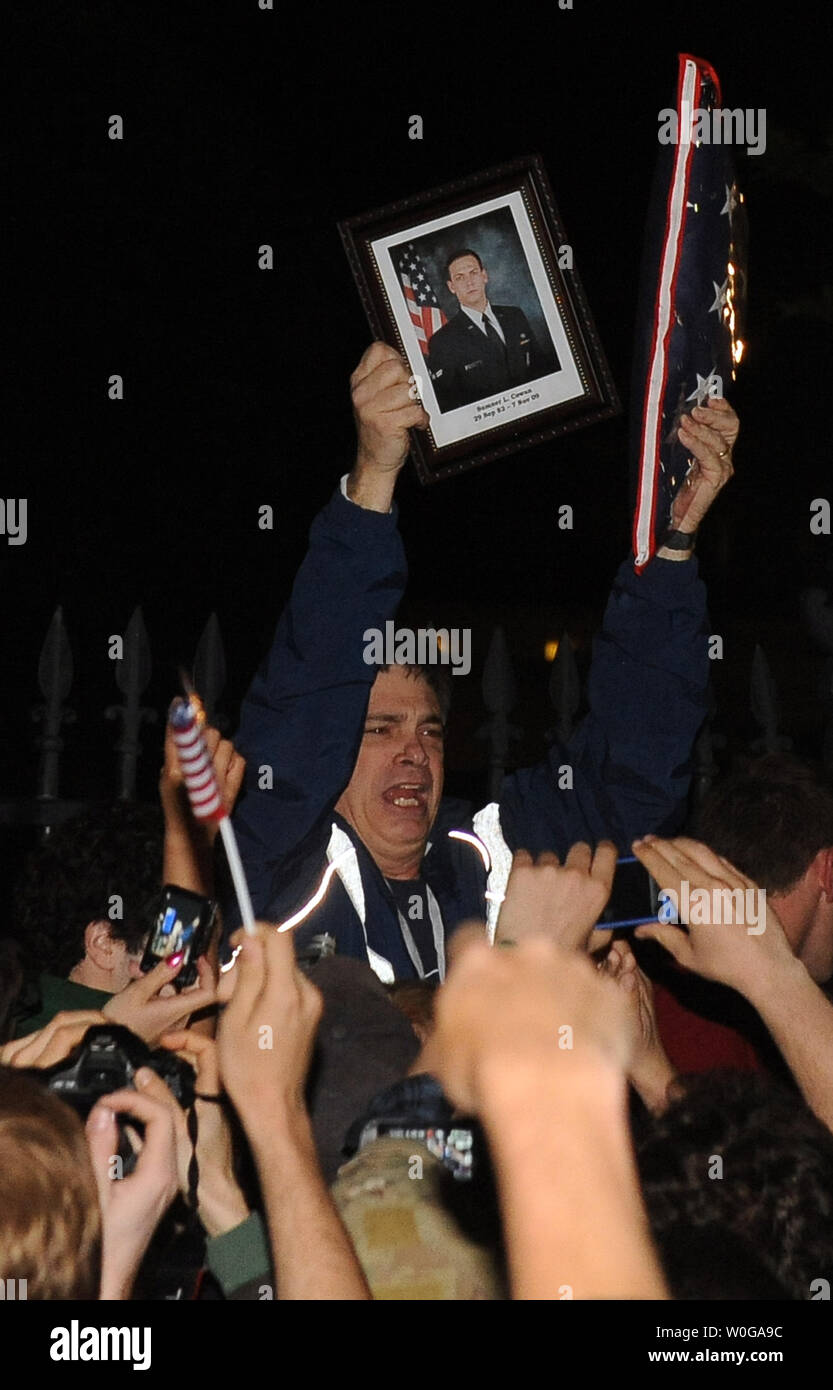 A man holds up a photo and flag of a fallen U.S. Air Force Senior ...