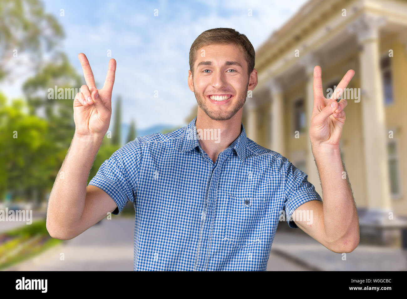 Attractive young man shows a sign of peace or victory Stock Photo - Alamy