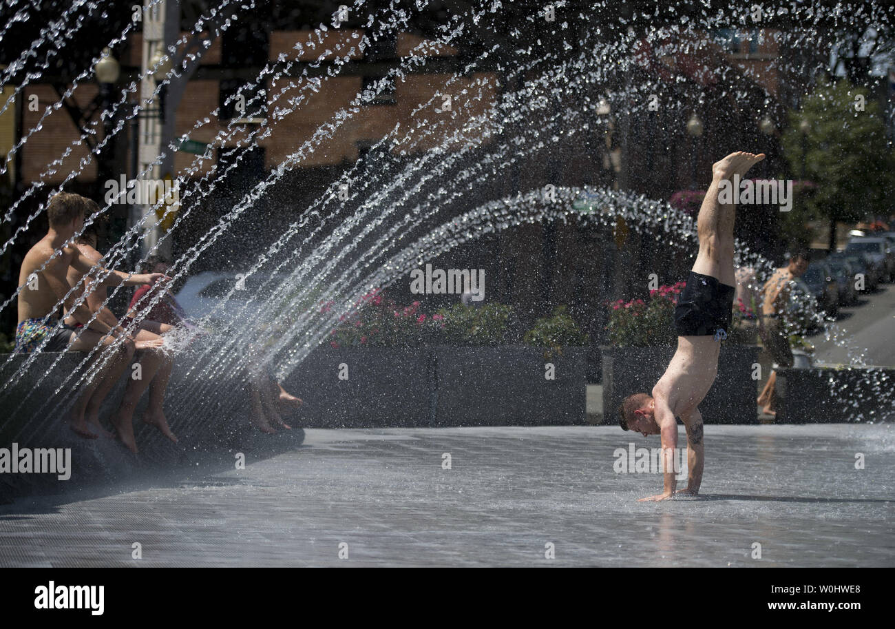People cool off in a fountain at the Georgetown Waterfront Park as ...