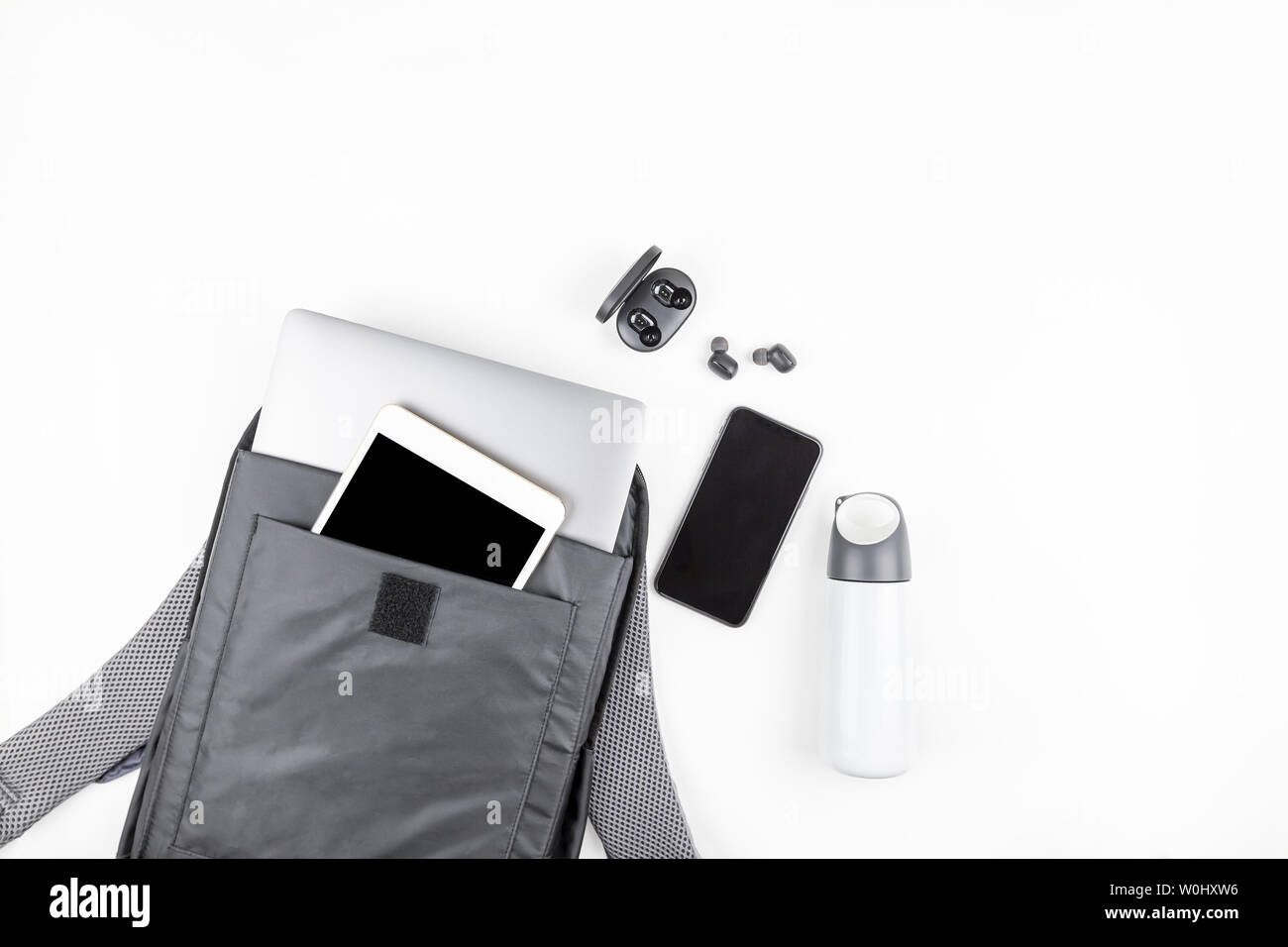 Creative top view flat lay of open backpack with laptop and tablet ...