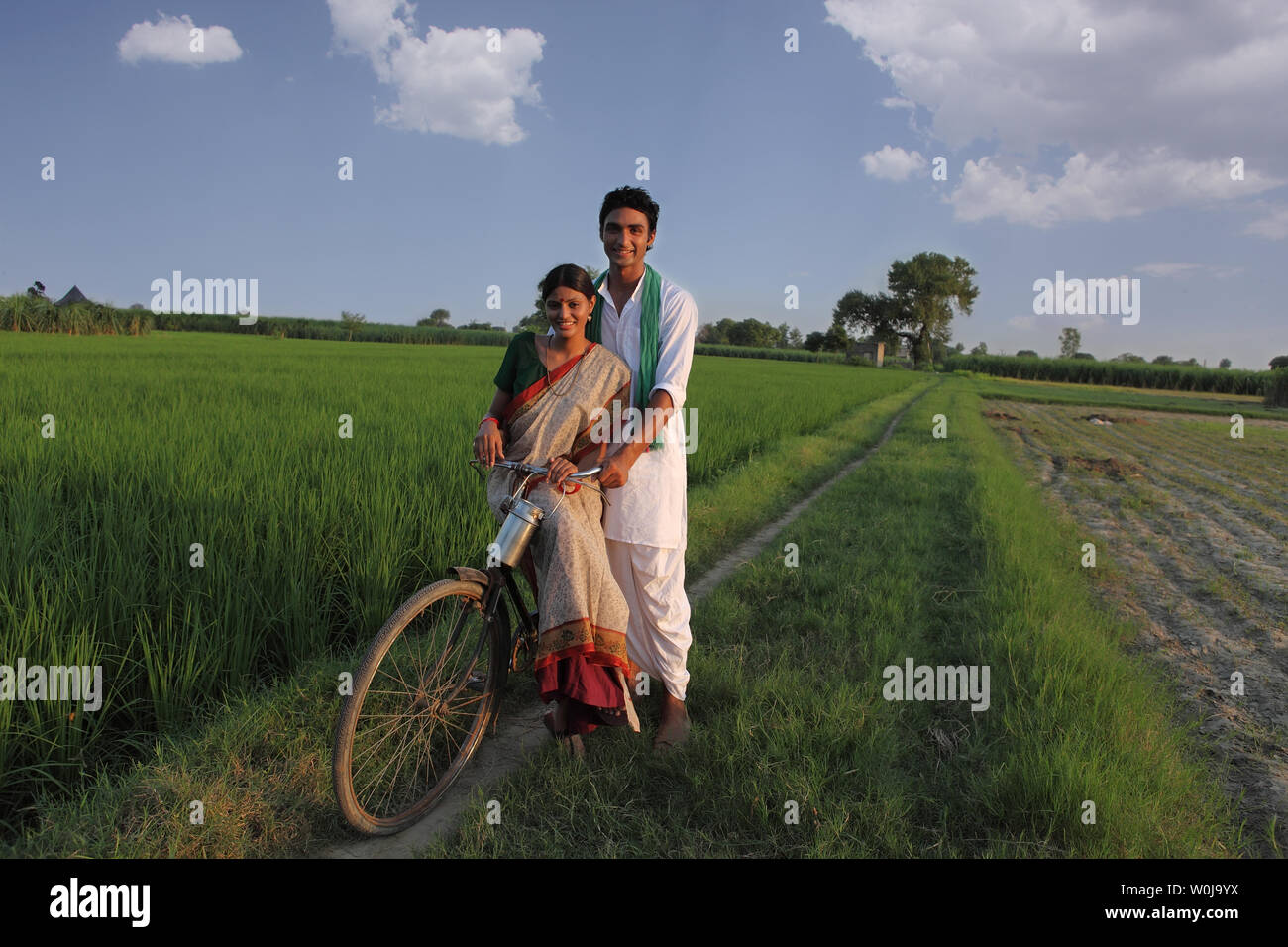 Rural couple riding on a bicycle in the field Stock Photo - Alamy