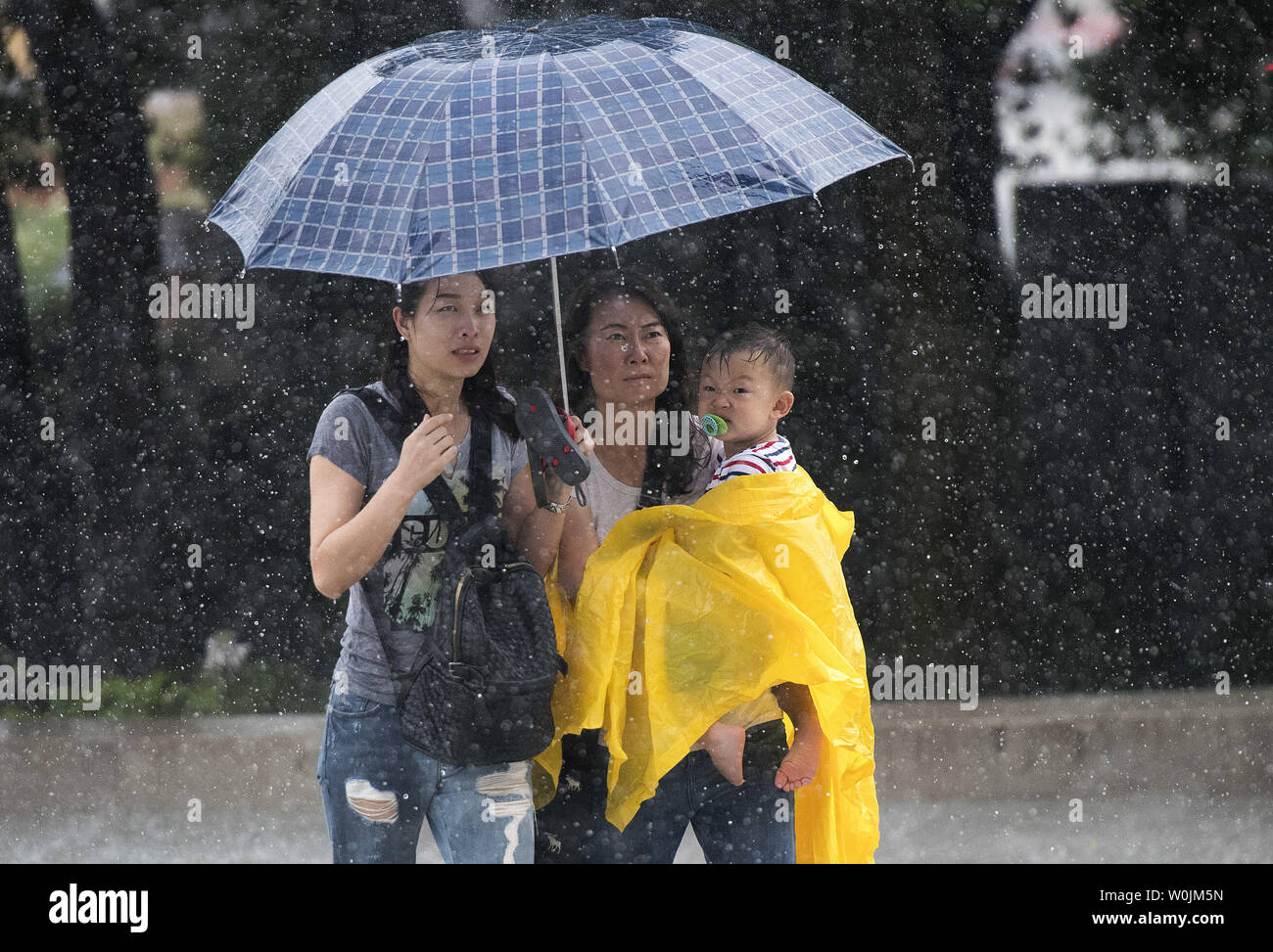People take cover under an umbrella as heavy rain falls in Washington ...