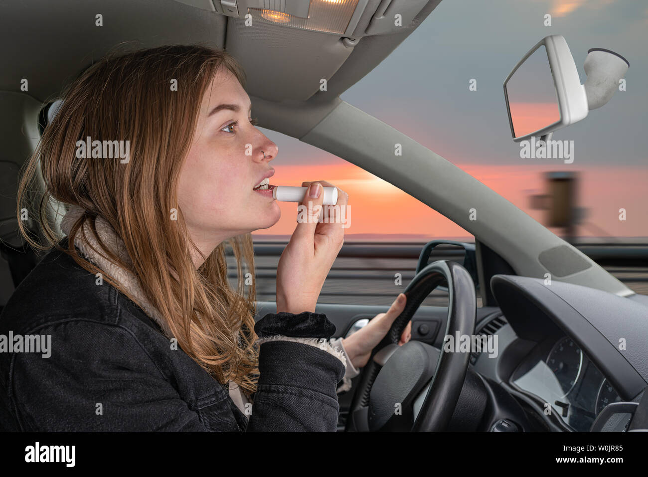 woman is distracted while driving and look into the driving morror ...