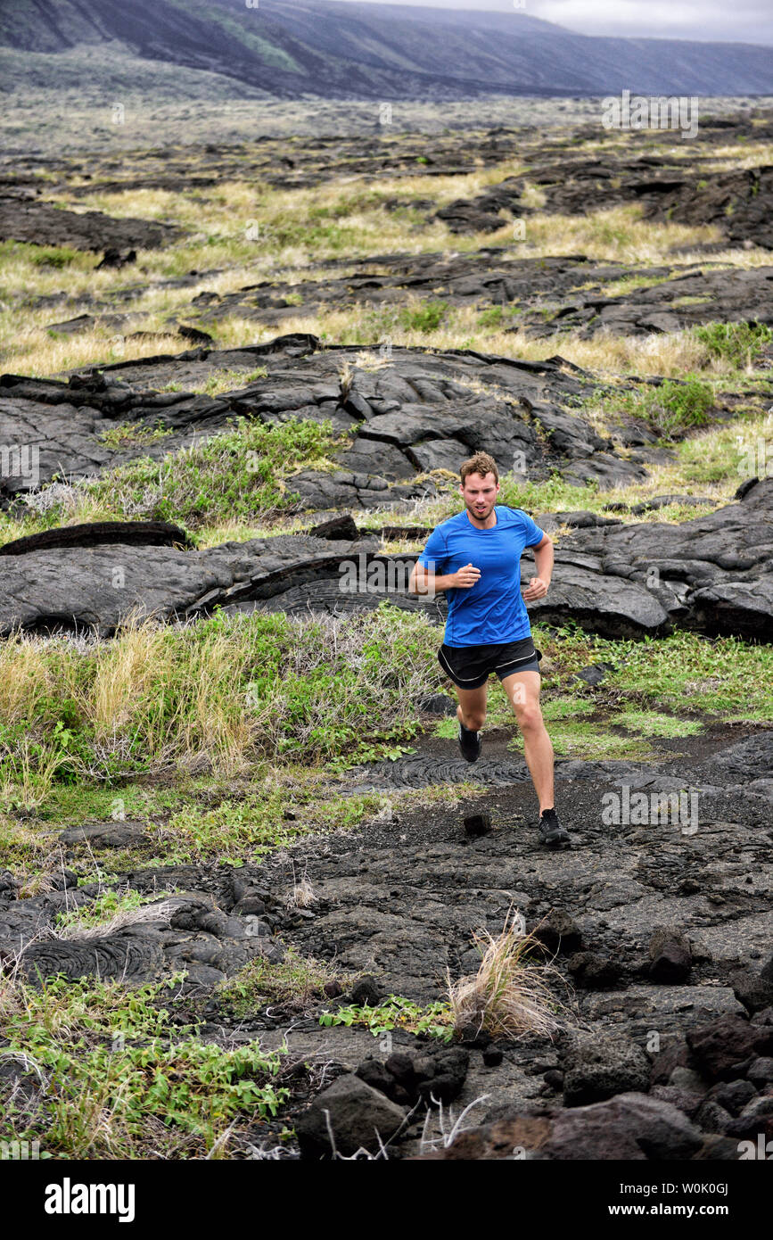 Active man trail running on volcanic rocks in mountain background. Male ...