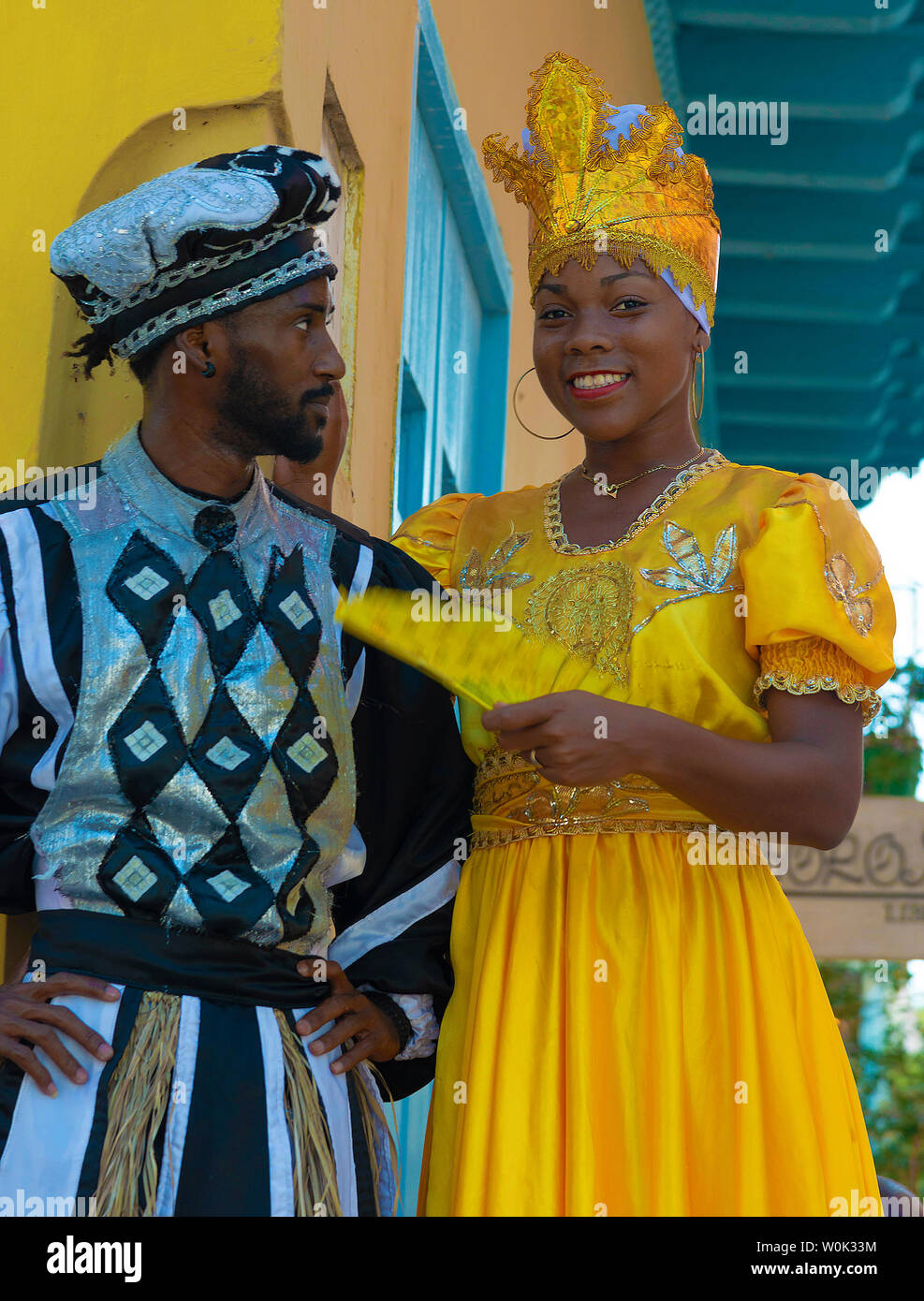 Colourfully dressed boy and pretty girl walking on stilts in one of the ...
