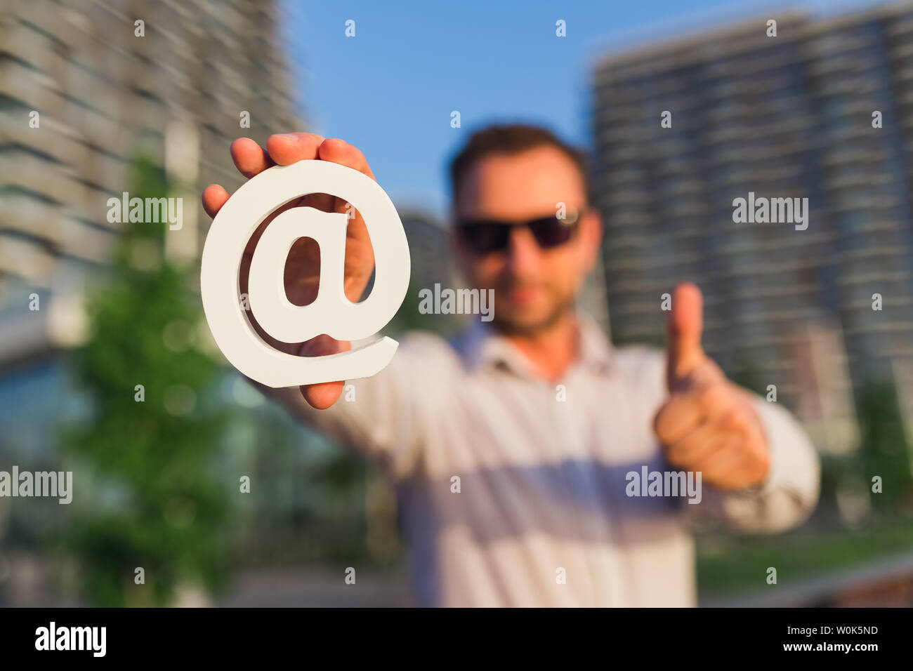 Businessman holding email symbol and showing thumbs up in front of ...