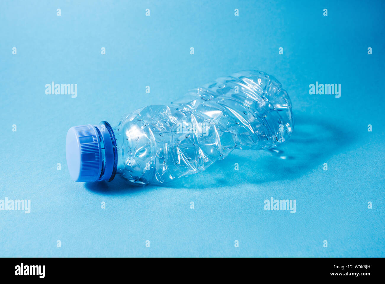 Used disposable plastic bottle on blue background. Eco concept image ...