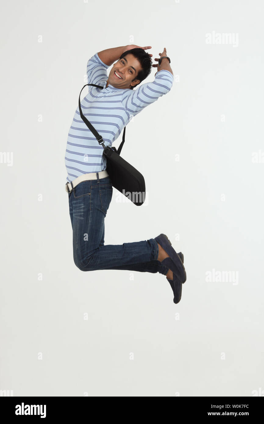 College student jumping in air and smiling Stock Photo - Alamy