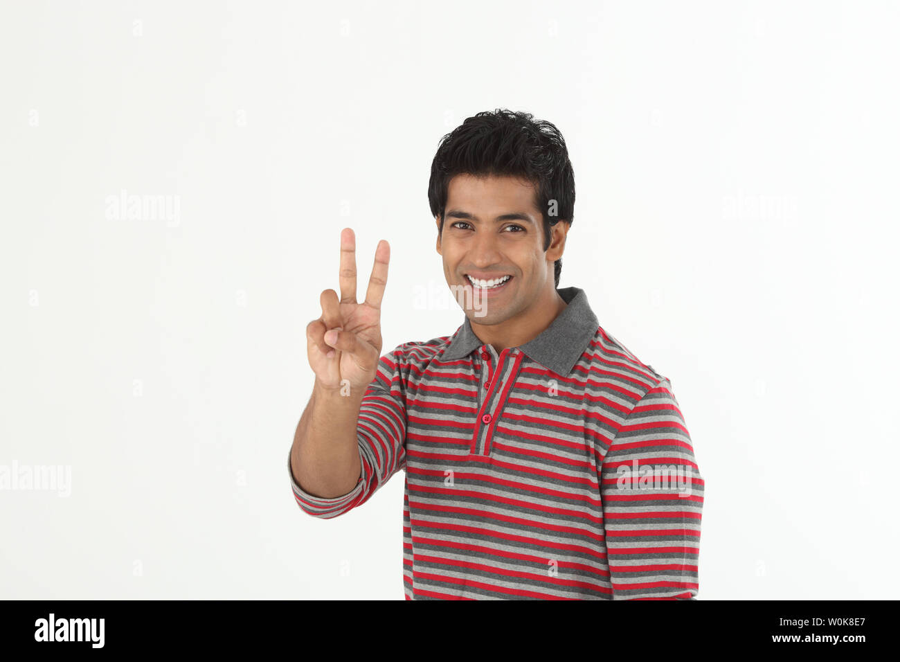 Portrait of a man showing v sign and smiling Stock Photo - Alamy