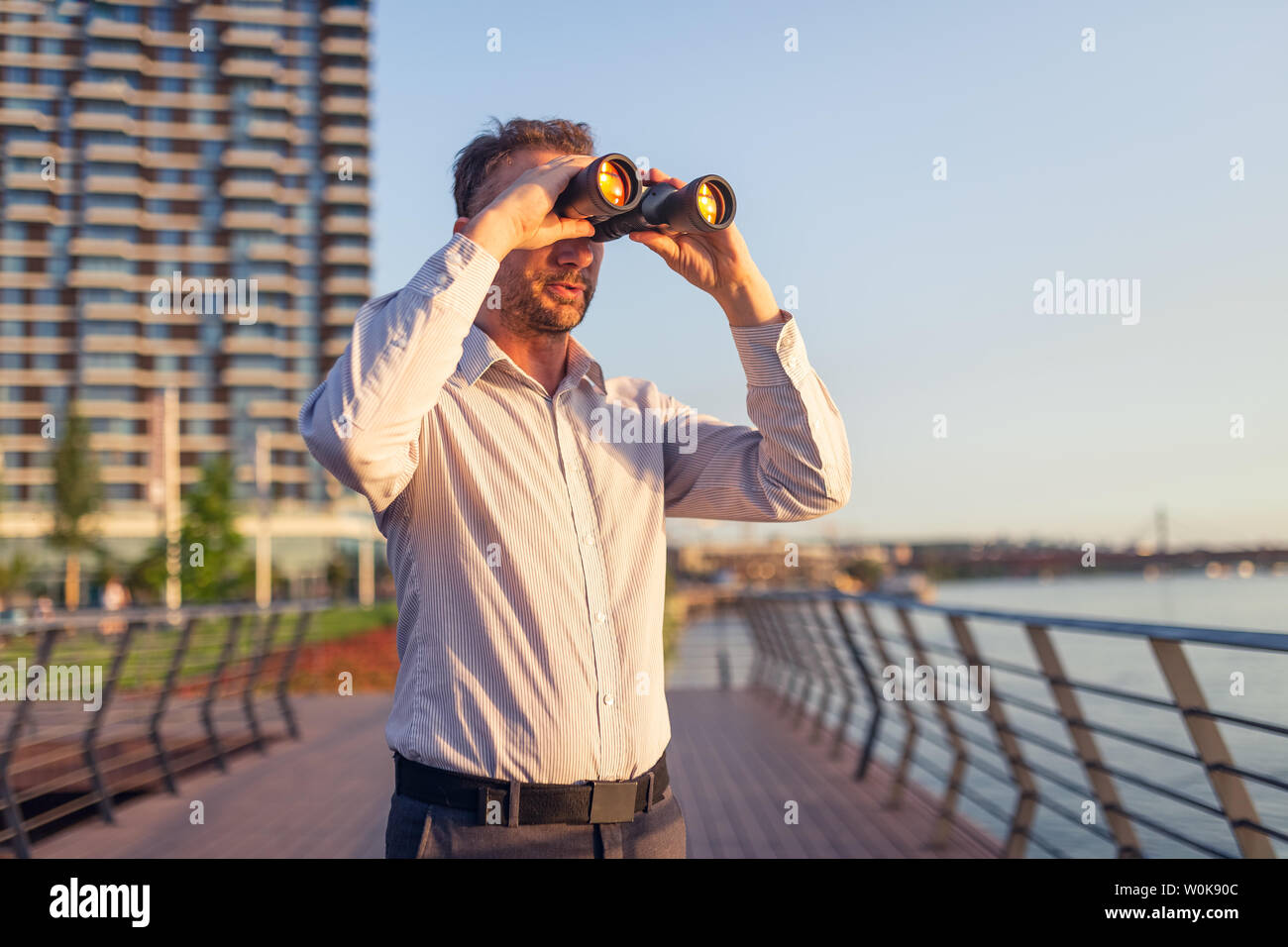 Business person looking through binoculars in front of business ...