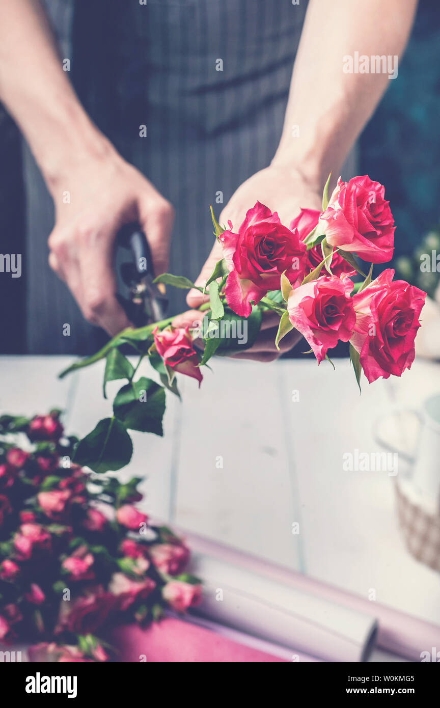Florist at work. Female hands collect a wedding bouquet of roses. Small ...