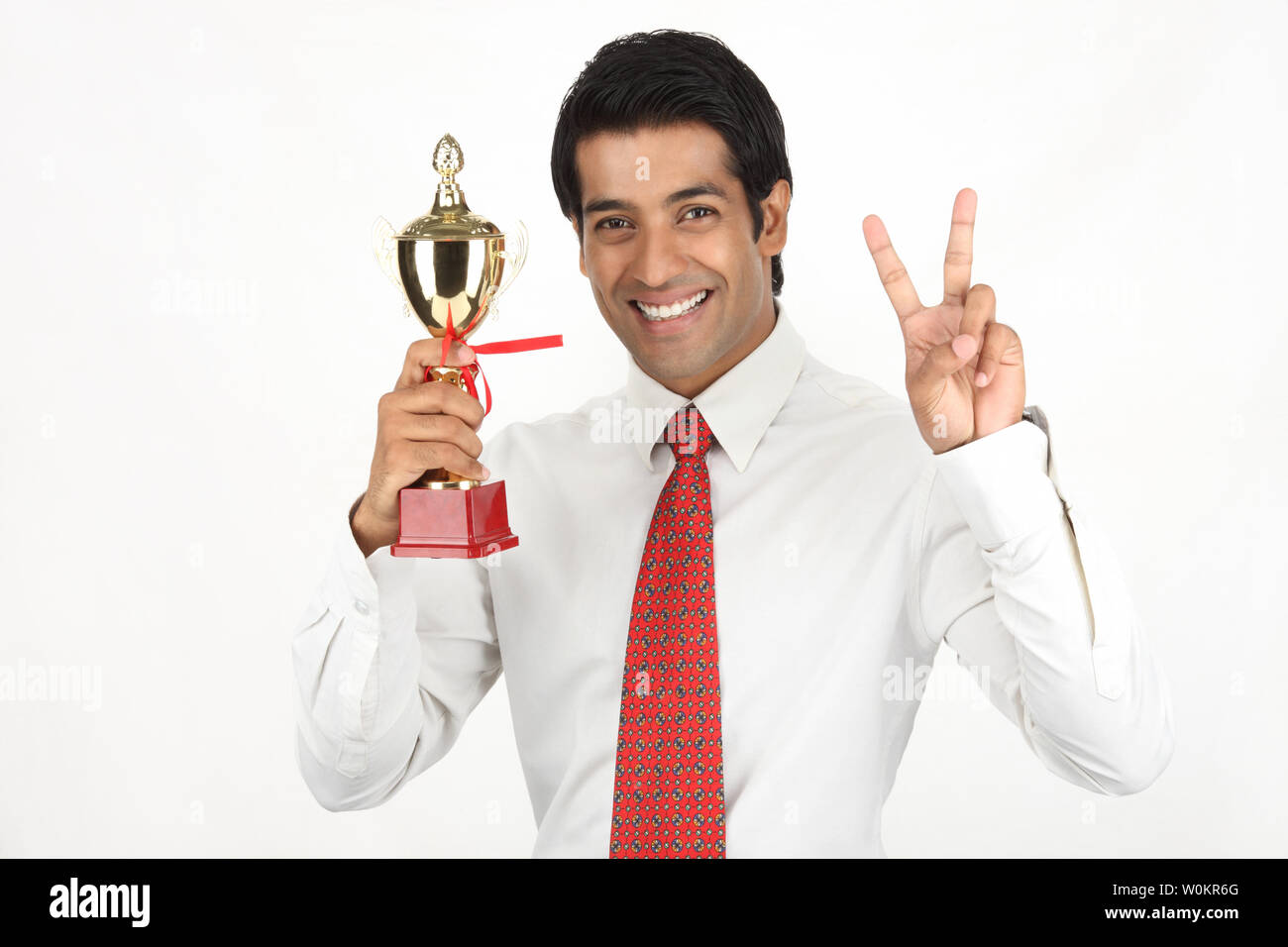 Businessman showing trophy and smiling Stock Photo - Alamy