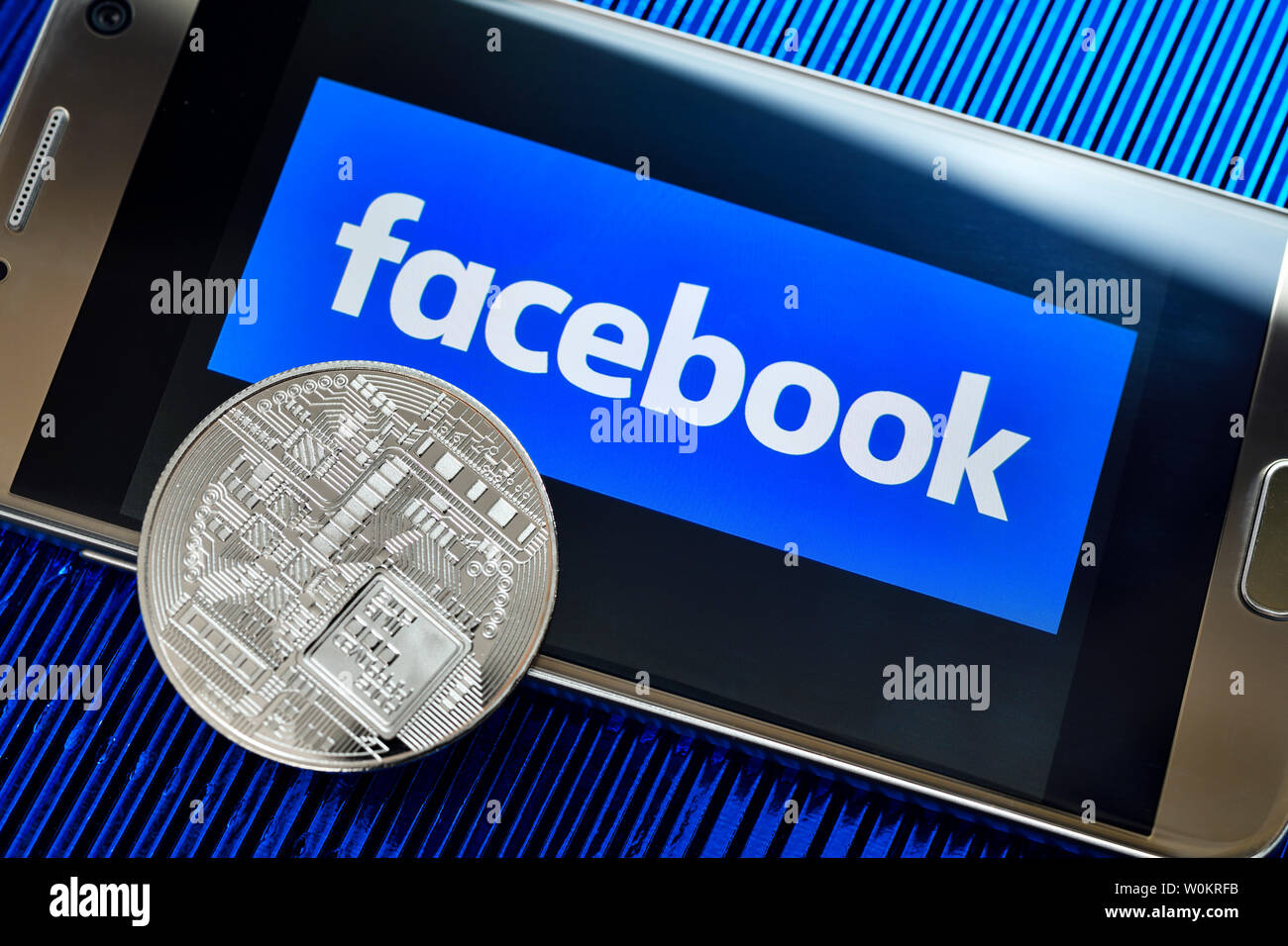 Facebook logo on a smartphone screen and coin, libra cryptocurrency ...