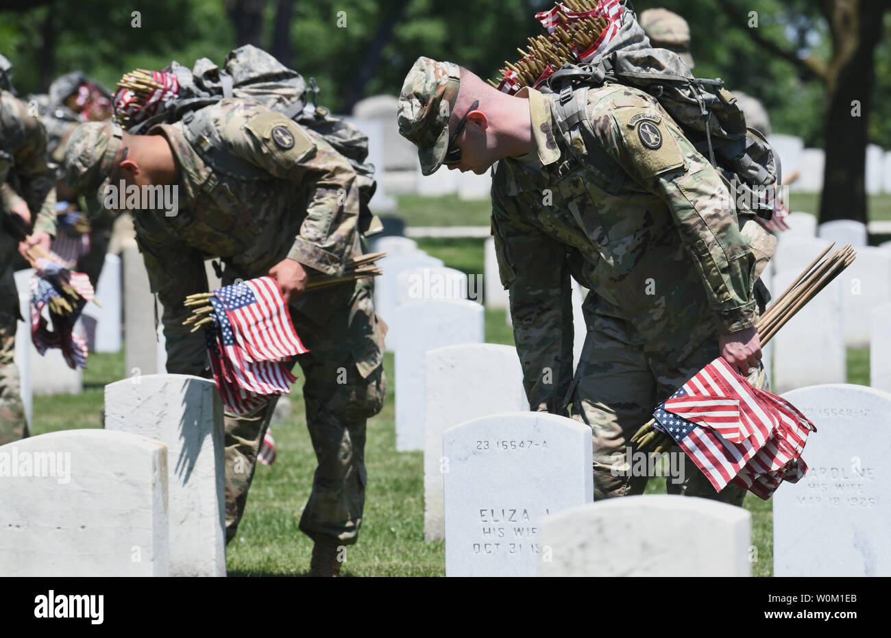 U.S. soldiers place flags near the tombstone of a fallen veteran at ...