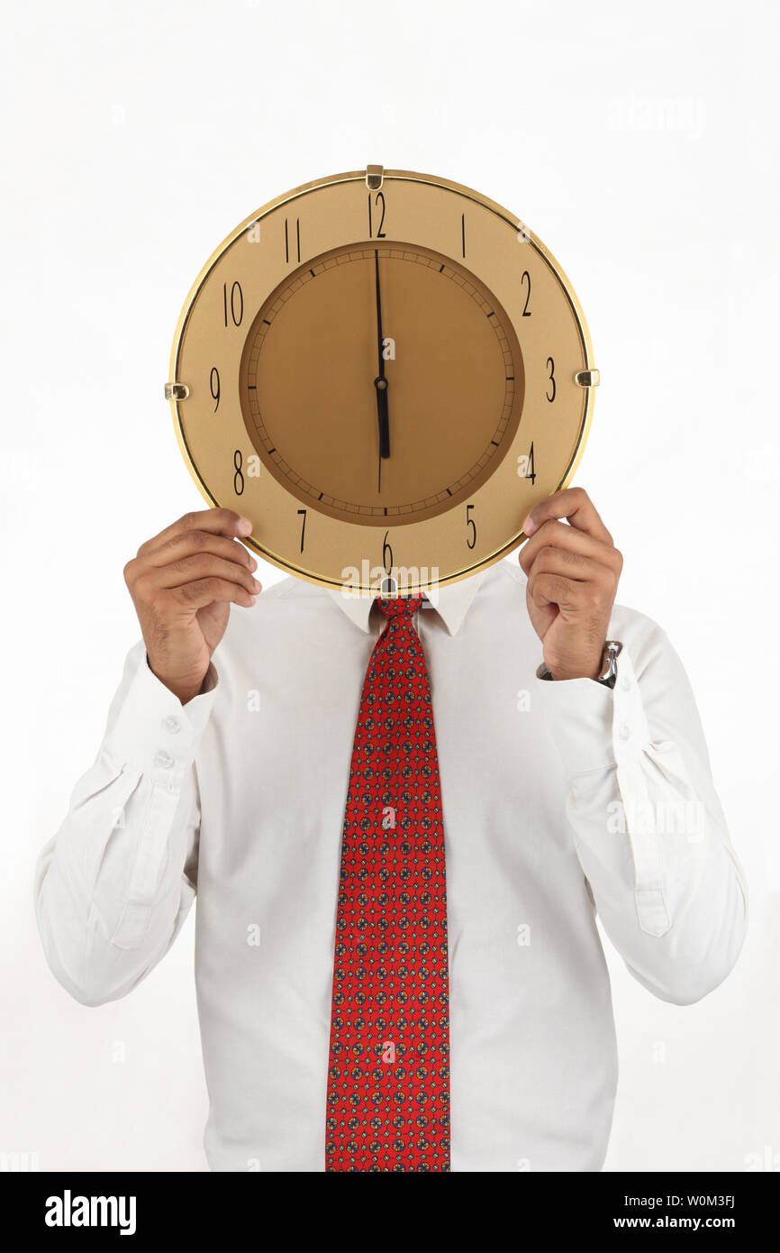 Businessman covering his face with wall clock Stock Photo - Alamy