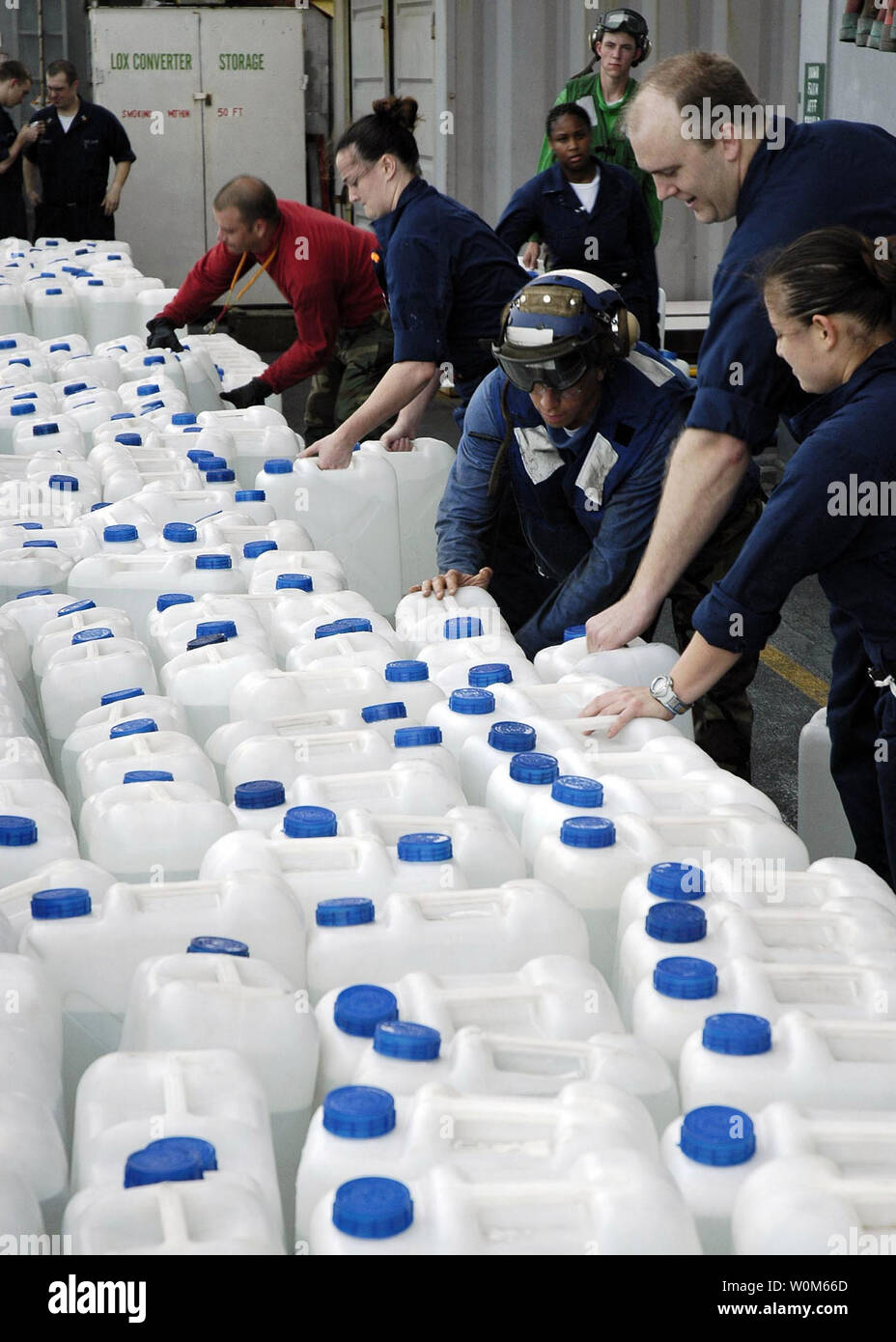 Sailors aboard the USS Abraham Lincoln fill jugs of purified water from ...