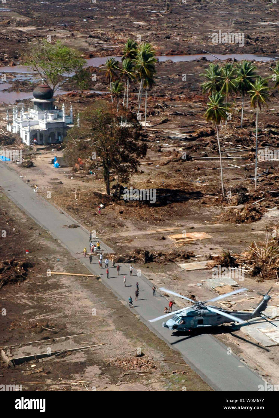 A US Navy helicopter lands to distribute relief supplies at a village ...