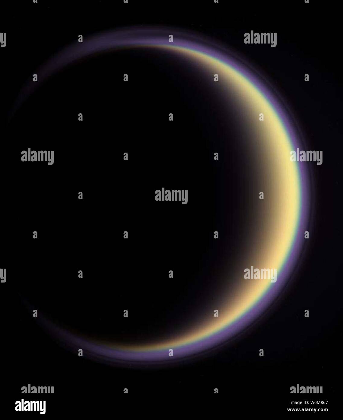 Titan's orange globe shines softly, encircled by a thin halo of purple ...